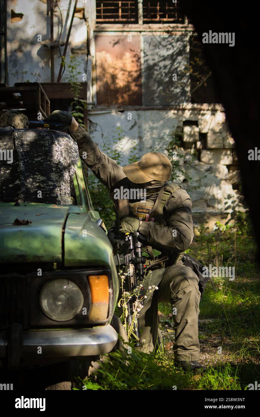 A tactical operator dressed in full military gear takes a knee behind ...