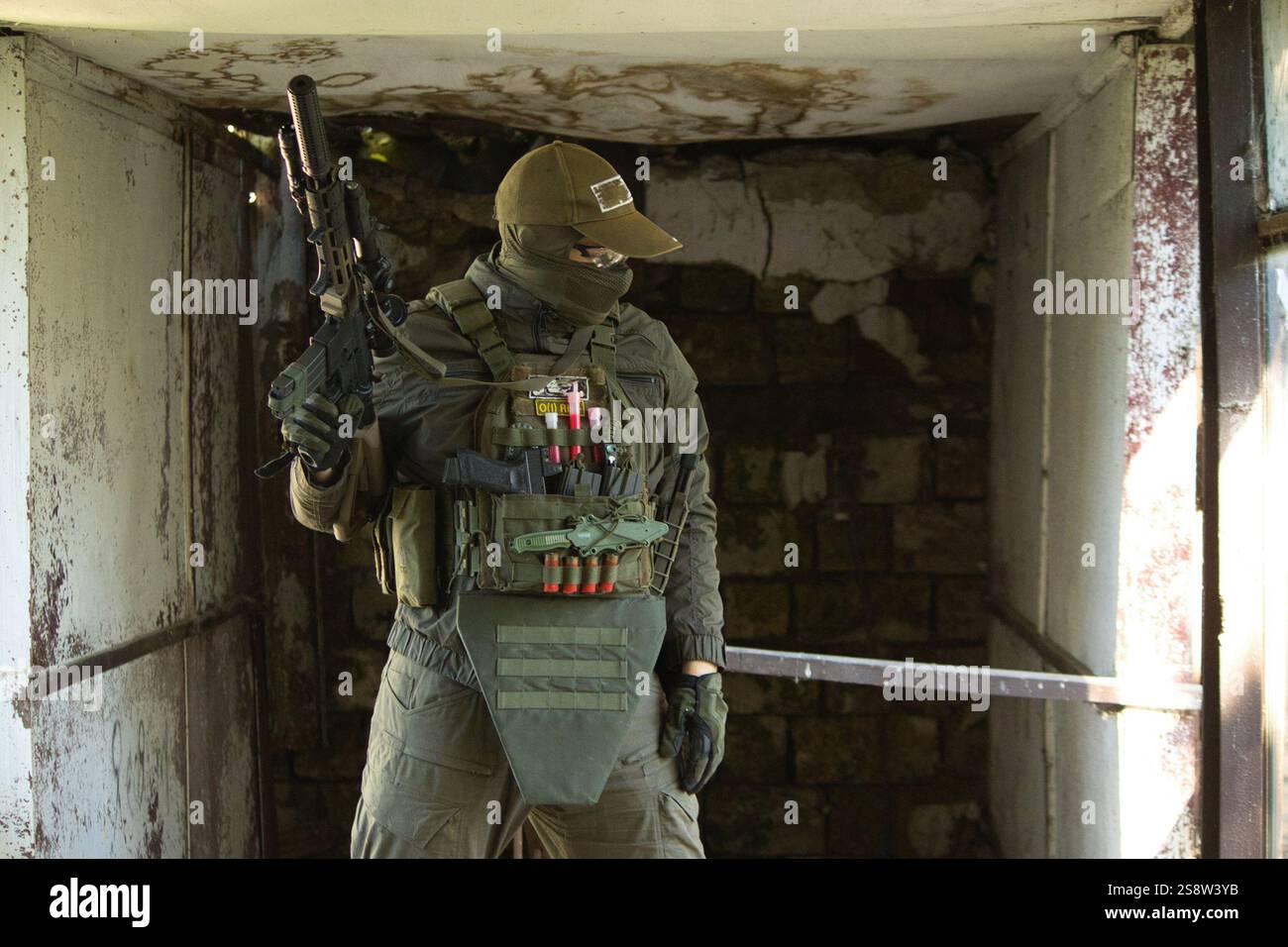 A tactical operator in green military gear aims through a scope while ...