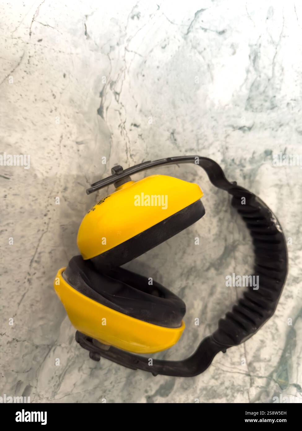 Protective ear muffs resting on a textured surface in a well-lit area ...