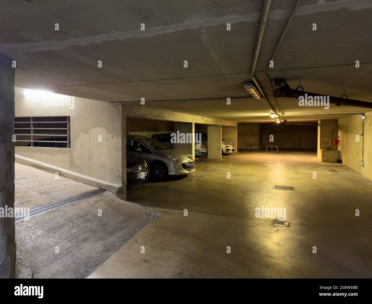 Underground parking garage with multiple vehicles and dim lighting in ...