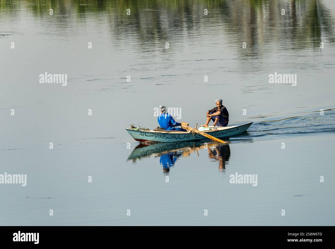Luxor, Egypt - 1 November 2024: Two men row their small boat on a calm ...