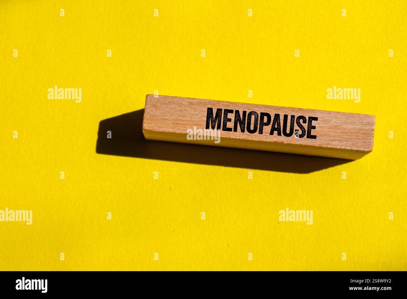 Menopause message written on wooden block on yellow background ...