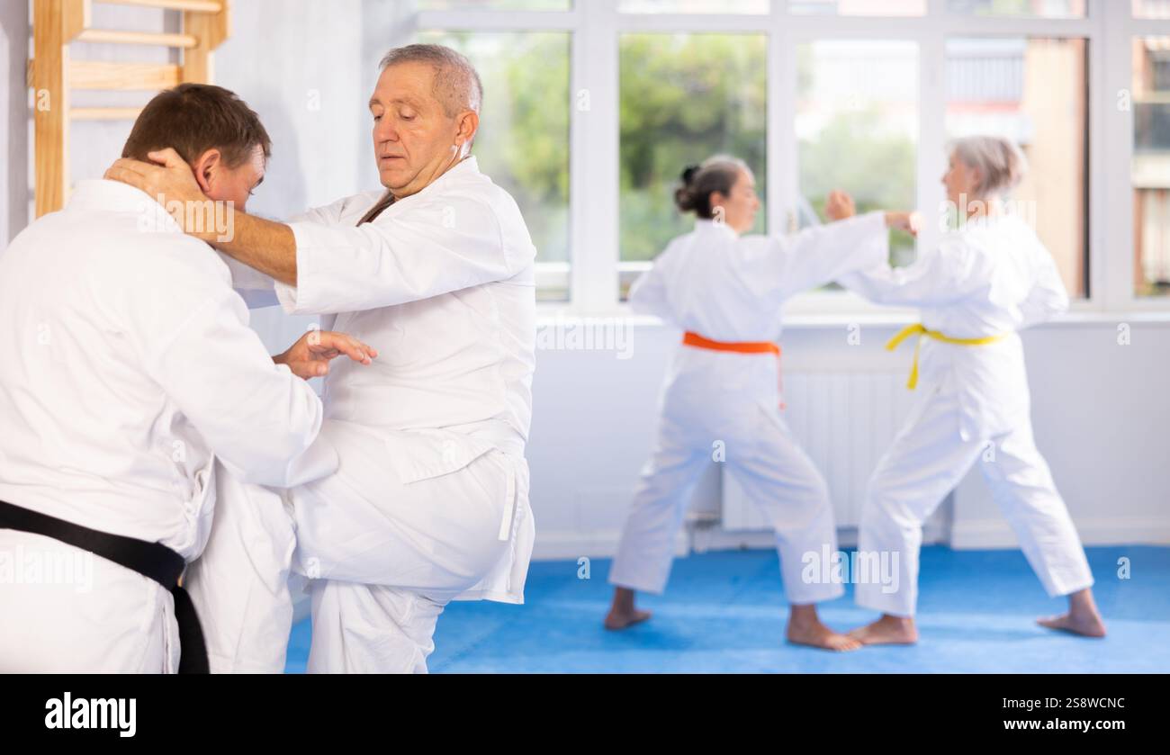 Old man attendee of karate classes fighting with his opponent in sports ...