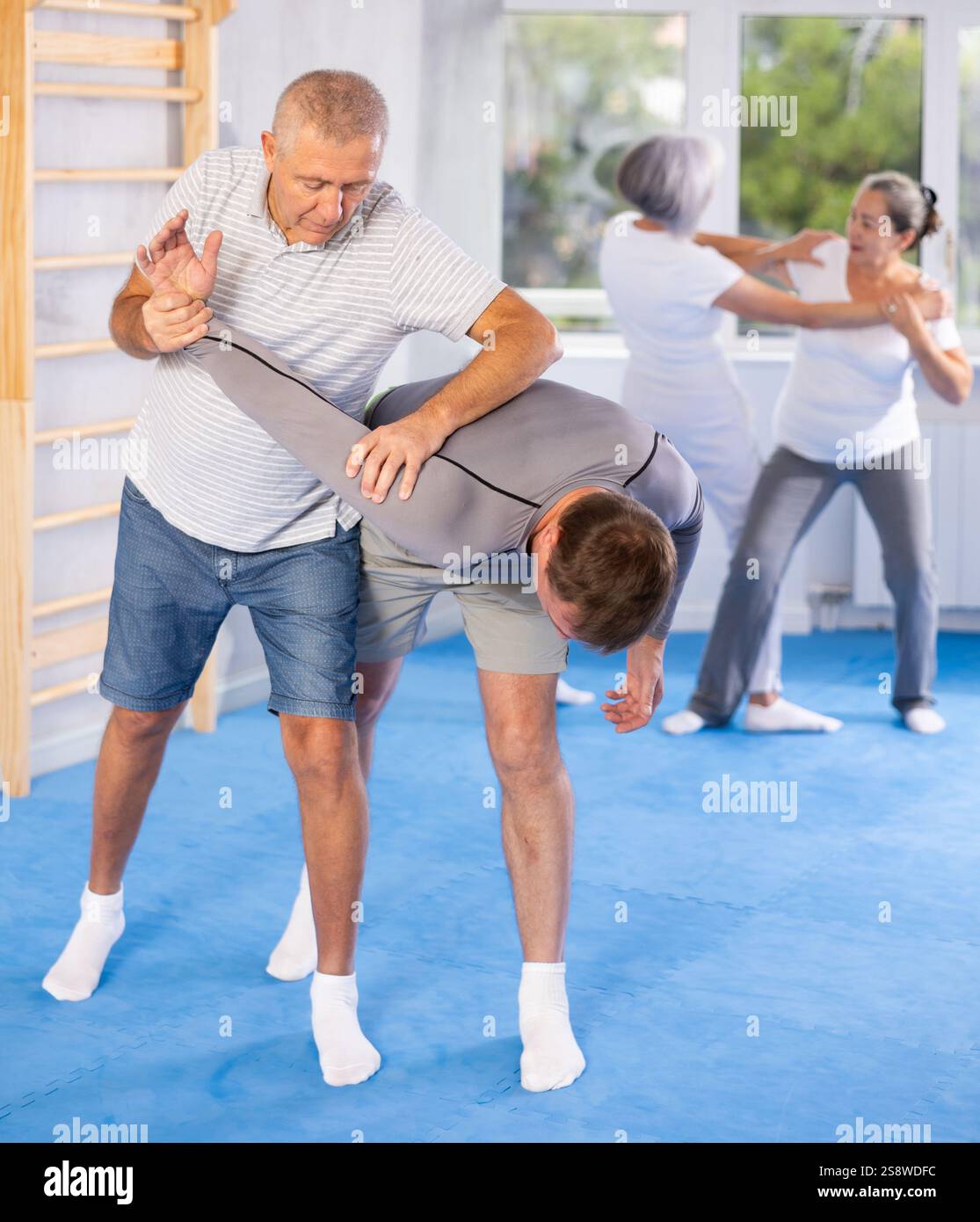 Senior man in pair with middle-aged coach train Krav Maga and self-defense skills Stock Photo ...