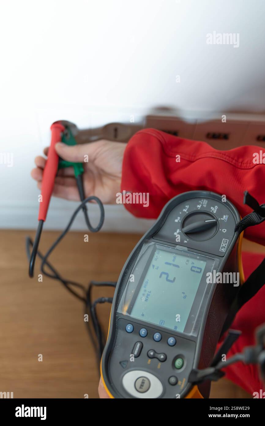 Electrician tests socket voltage with a specialized device, ensuring ...