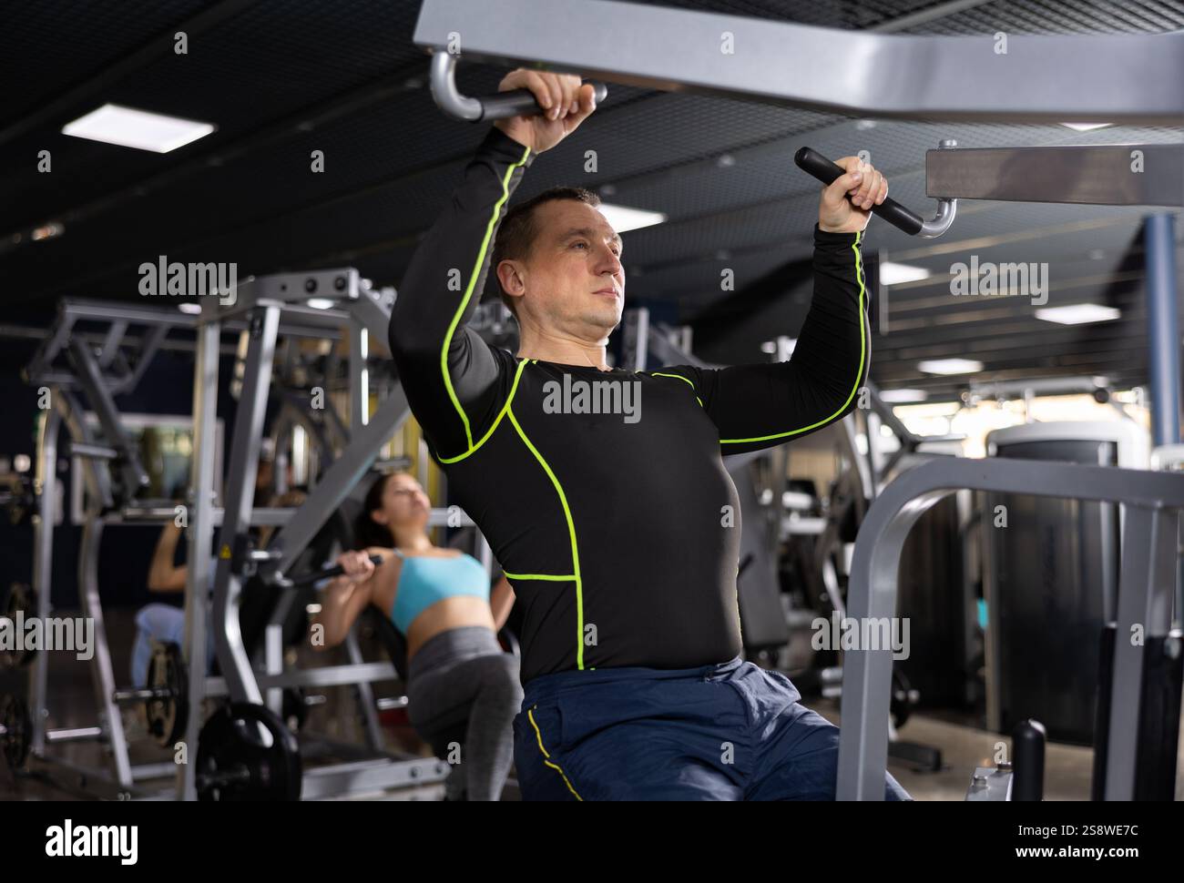 Man exercising back on pull down lever machine in gym Stock Photo - Alamy