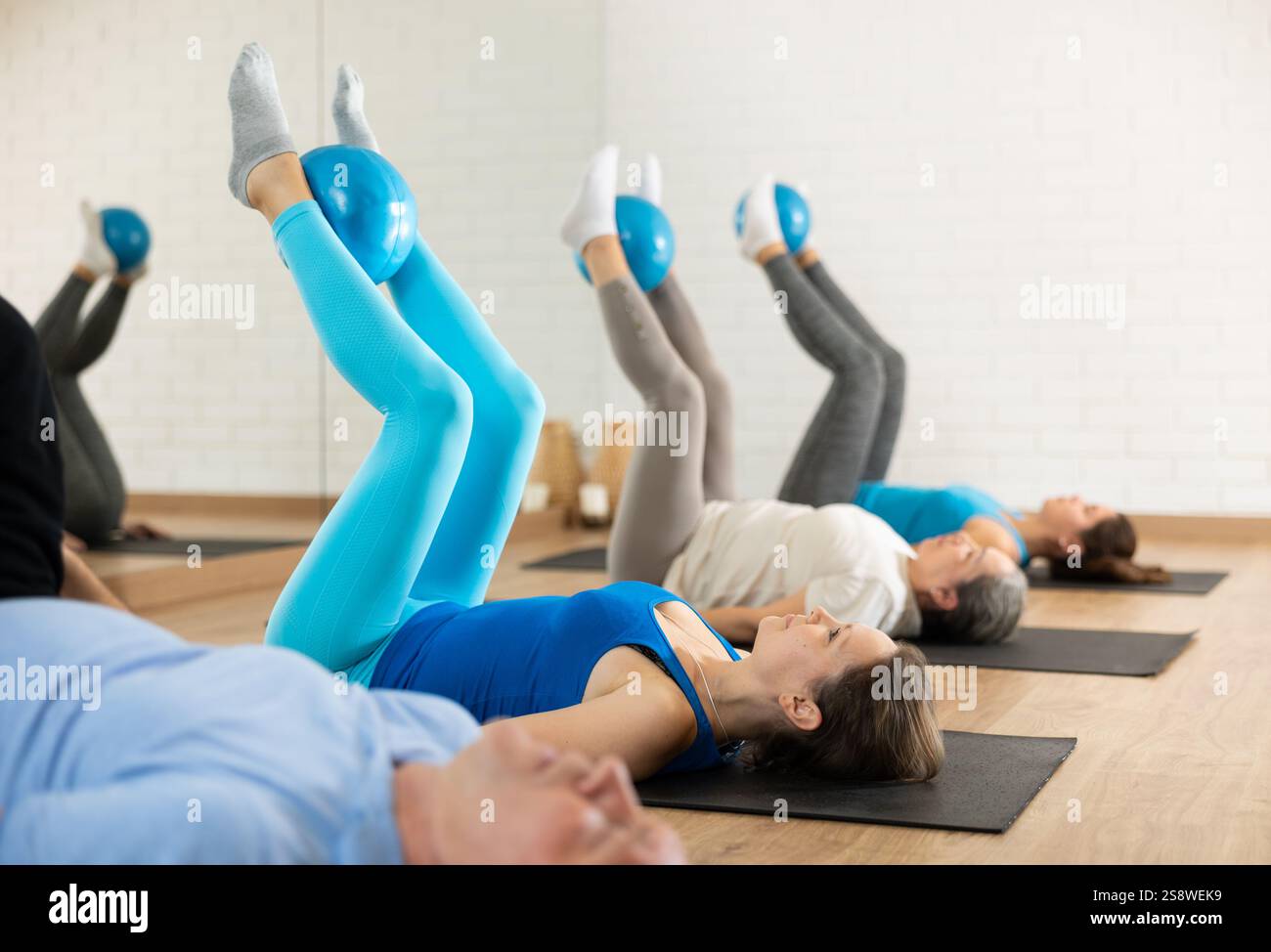 Class of people of different ages holding balls between legs and ...