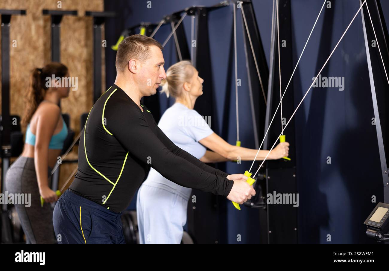 Man exercising back muscles on ski machine in gym Stock Photo - Alamy