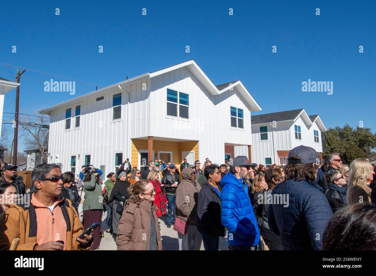 City officials and new residents gather to celebrate the grand opening of 12 Habitat for ...