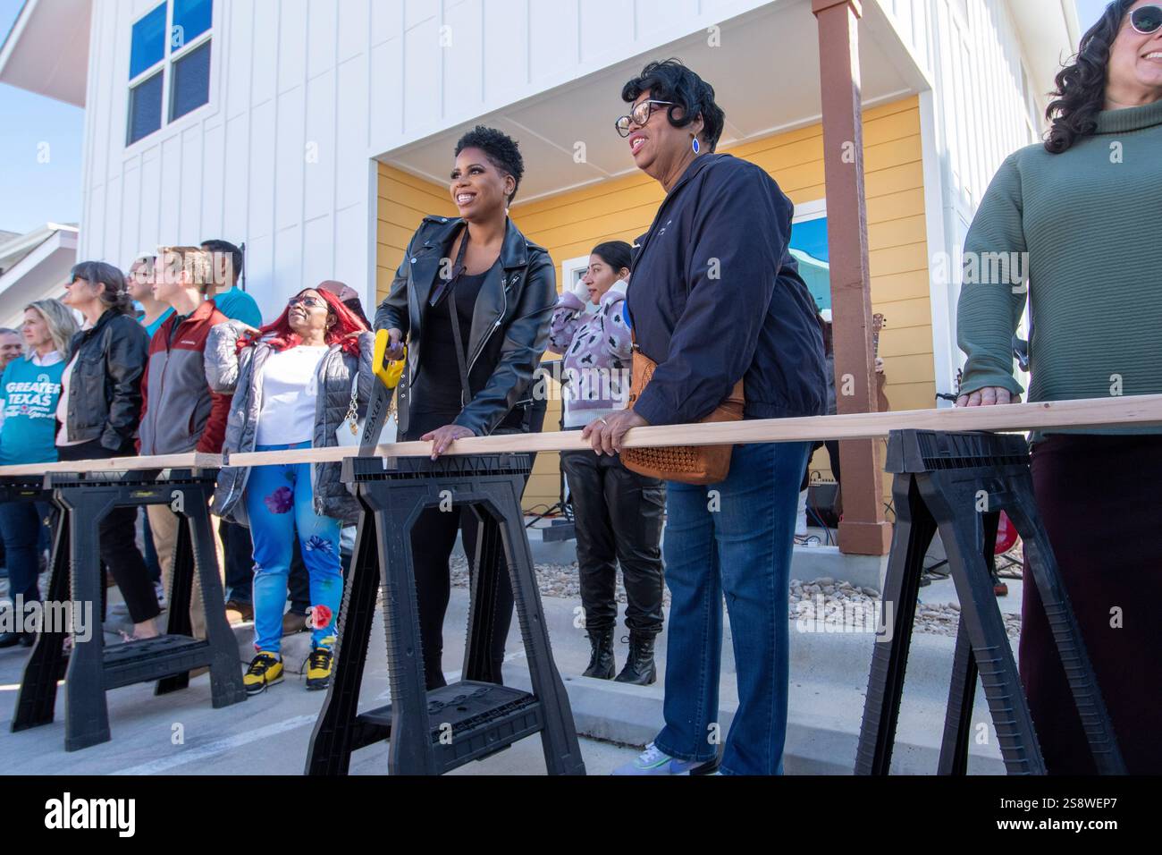 City officials and new residents gather to celebrate the grand opening of 12 Habitat for ...
