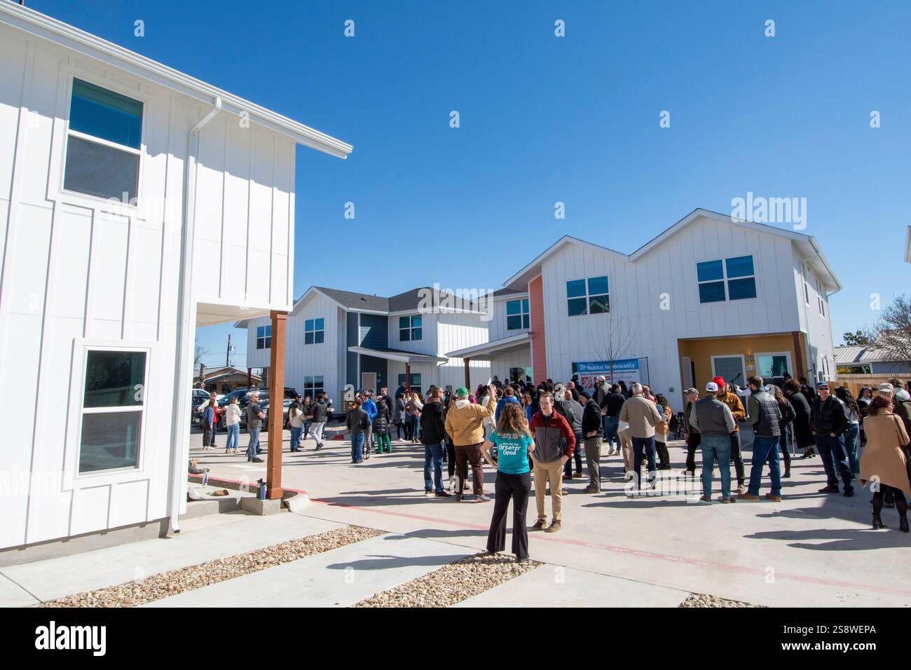 City officials and new residents gather to celebrate the grand opening of 12 Habitat for ...