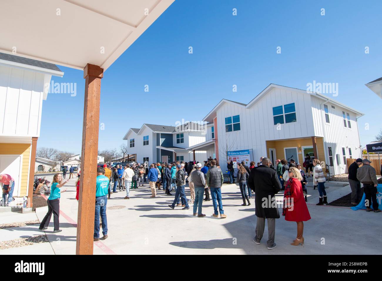 City officials and new residents gather to celebrate the grand opening of 12 Habitat for ...