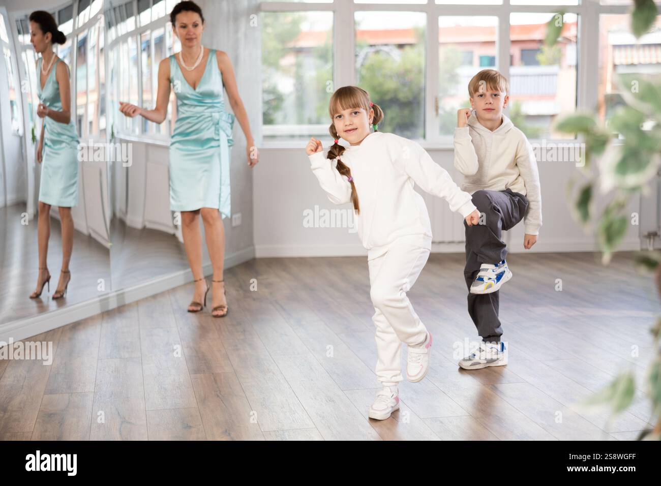 Tween girl and boy rehearsing popping techniques in street dance studio ...