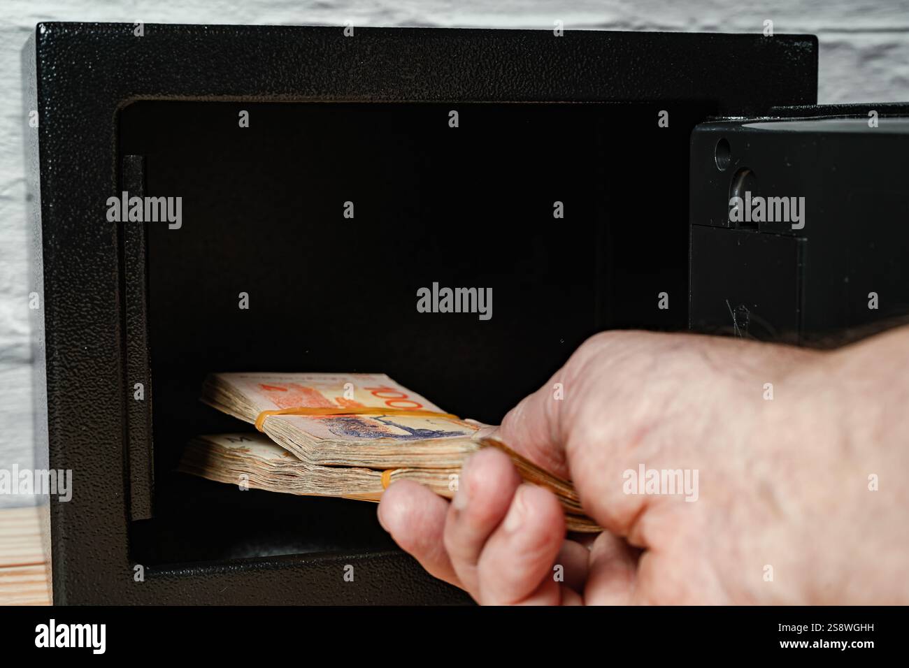 Man taking wads of cash from inside an open safe deposit box Stock ...
