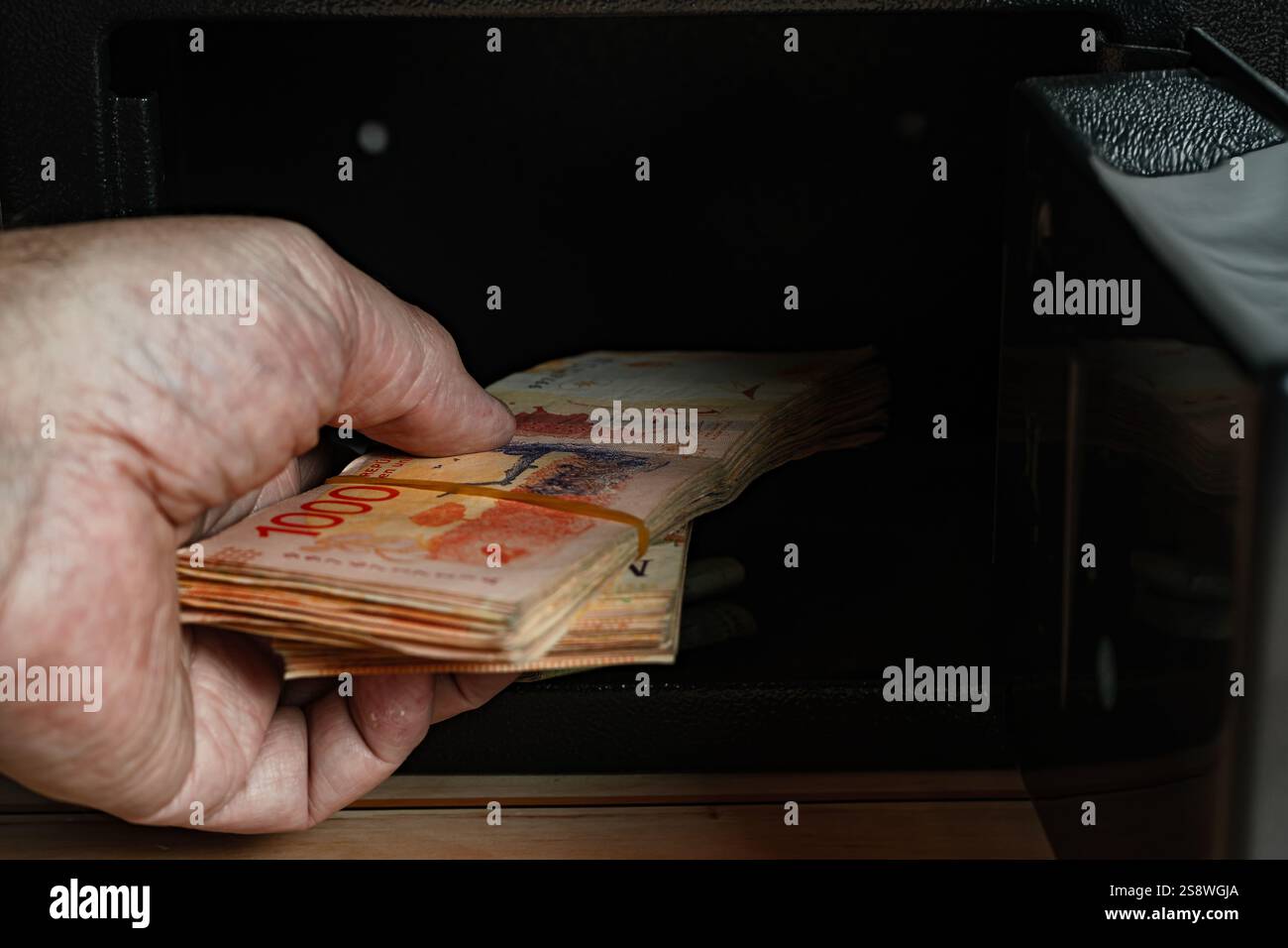 Man taking wads of cash from inside an open safe deposit box Stock ...