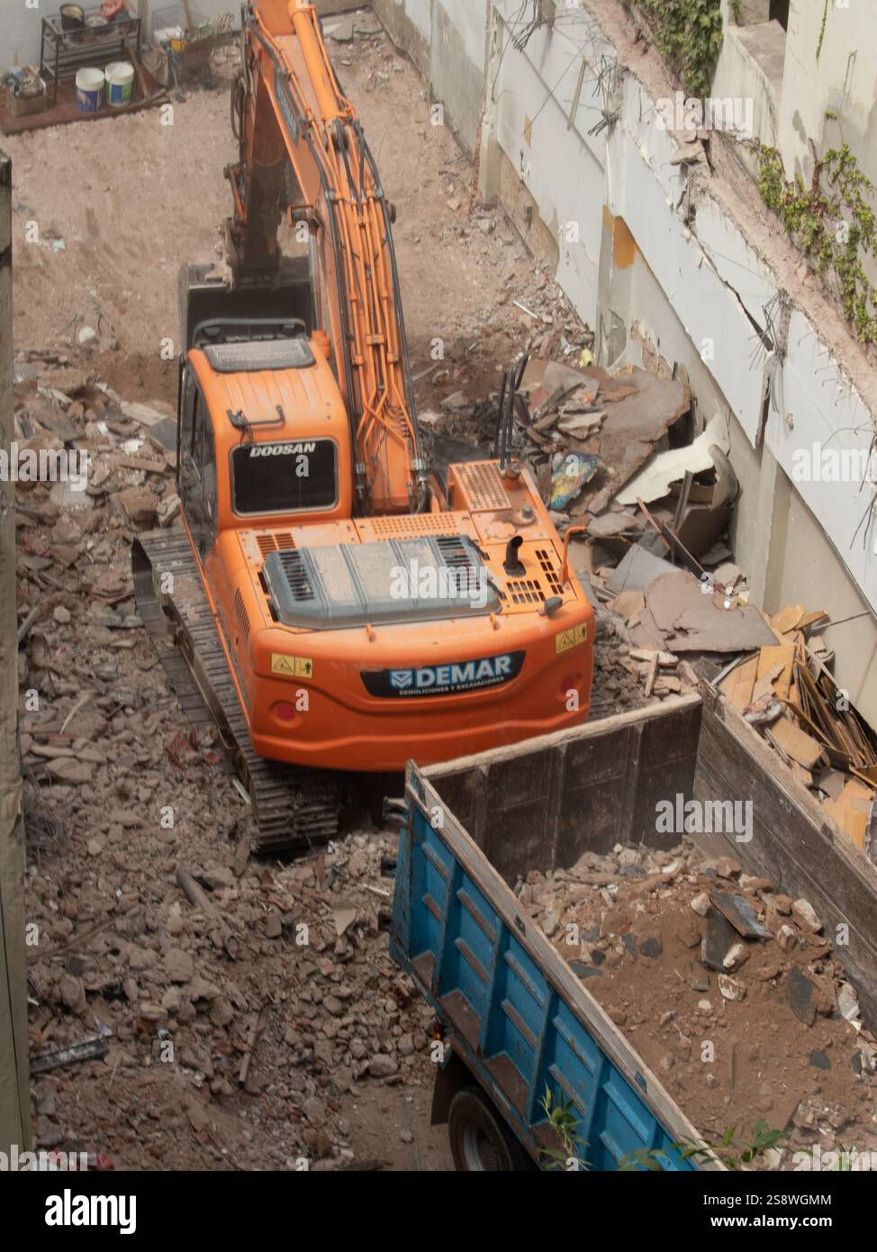 Excavator removing debris from a demolition site and dumping it into ...