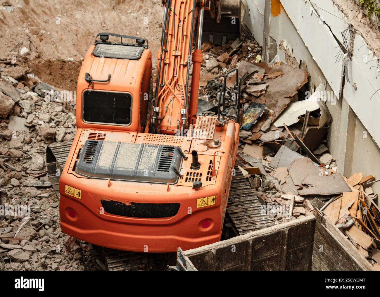 Excavator removing debris from a demolition site and dumping it into ...
