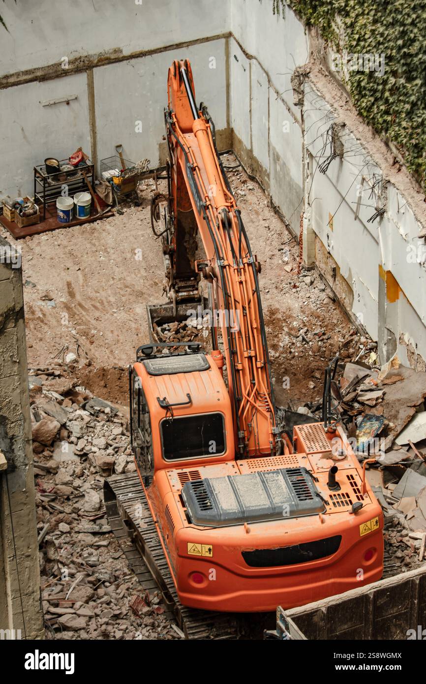 Excavator removing debris from a demolition site and dumping it into ...