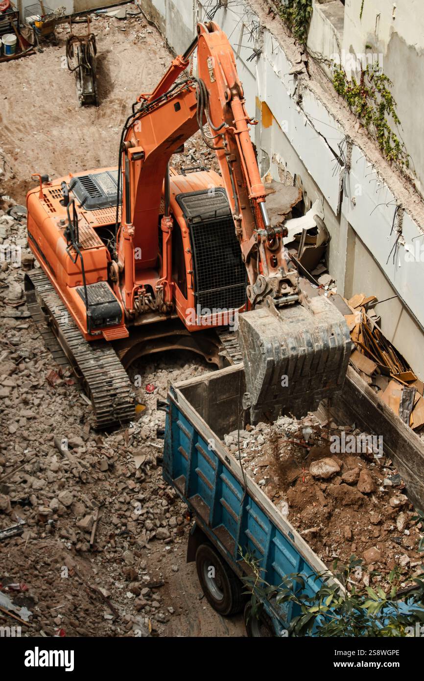 Excavator removing debris from a demolition site and dumping it into ...