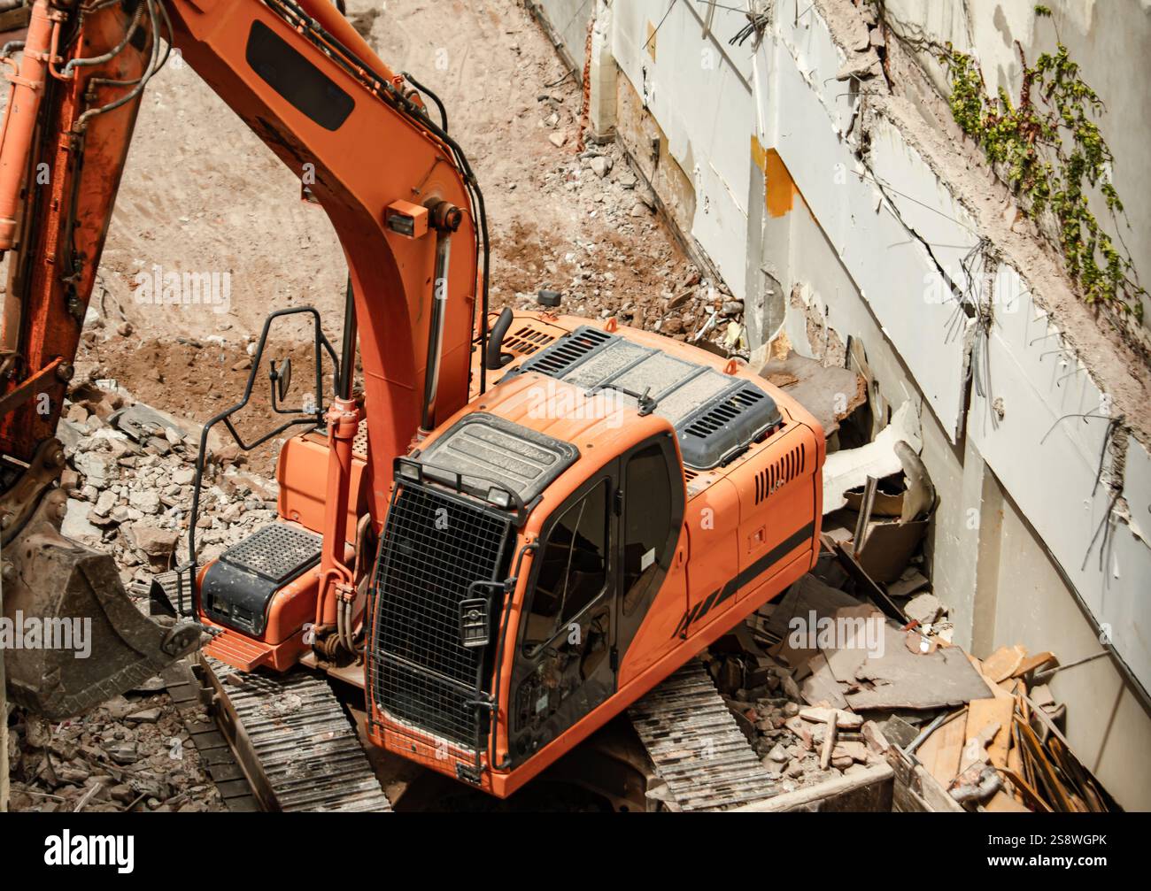 Excavator removing debris from a demolition site and dumping it into ...