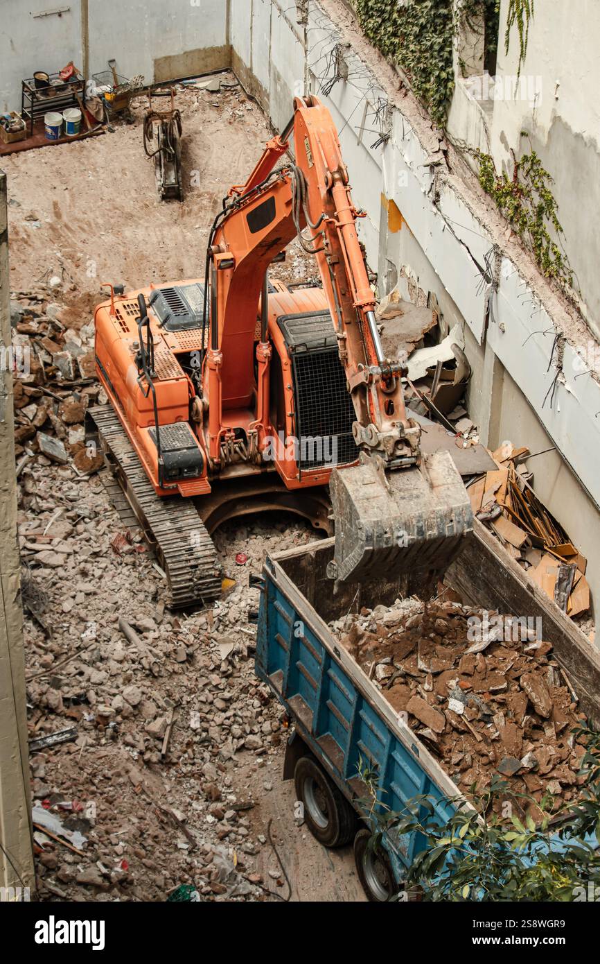 Excavator removing debris from a demolition site and dumping it into ...