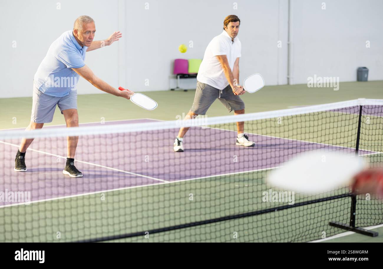 Elderly man playing pickleball in team with male partner indoors Stock ...