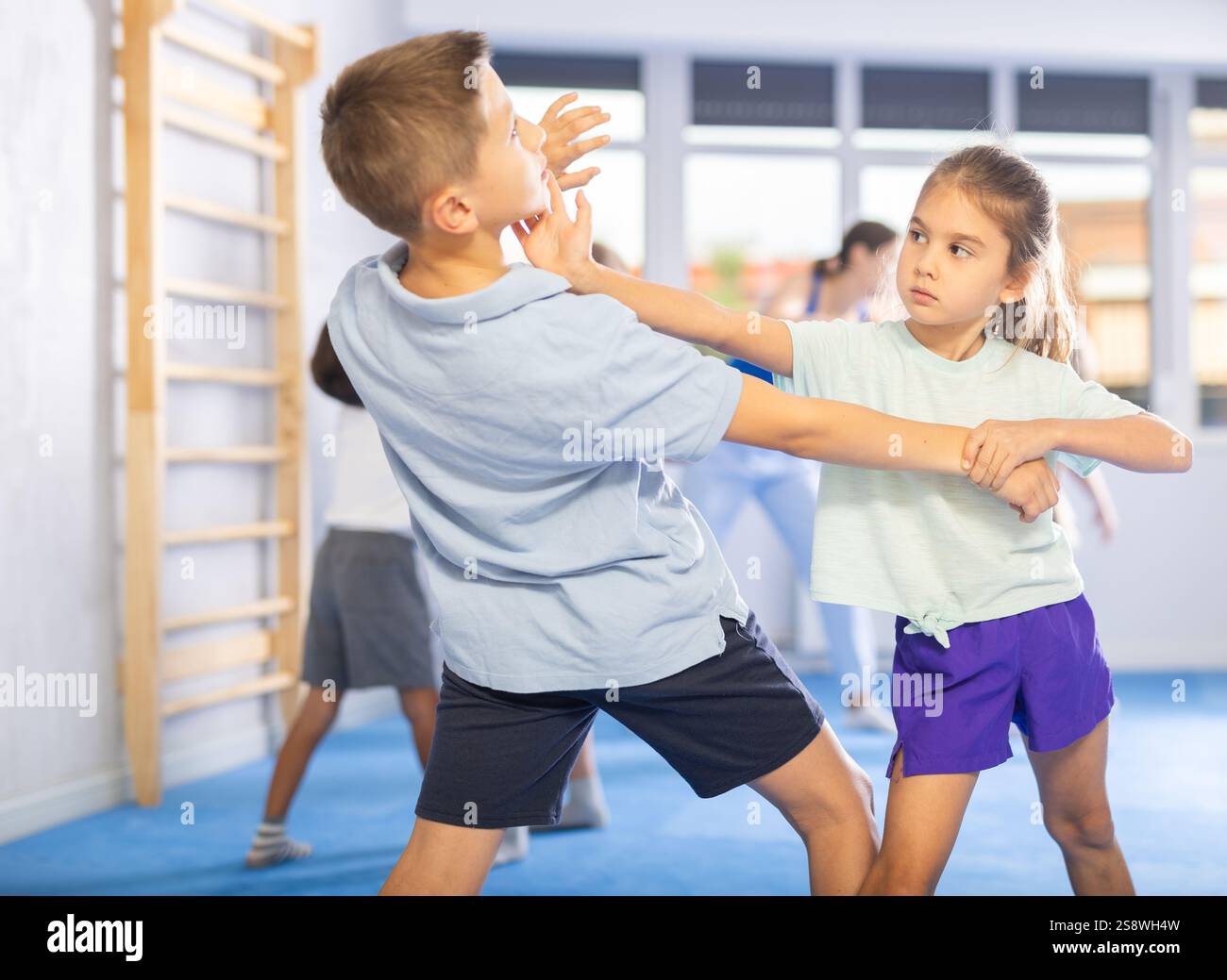 Boys and girls in gym perform basic elements of krav maga self-defense ...
