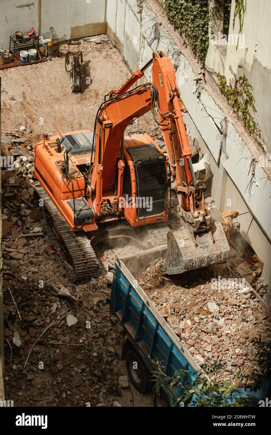 Excavator removing debris from a demolition site and dumping it into ...