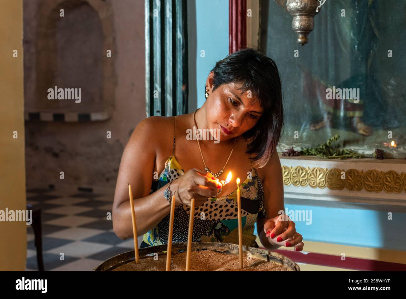 Woman light a candle inside Metamorphosis Sotiros church at Methoni ...