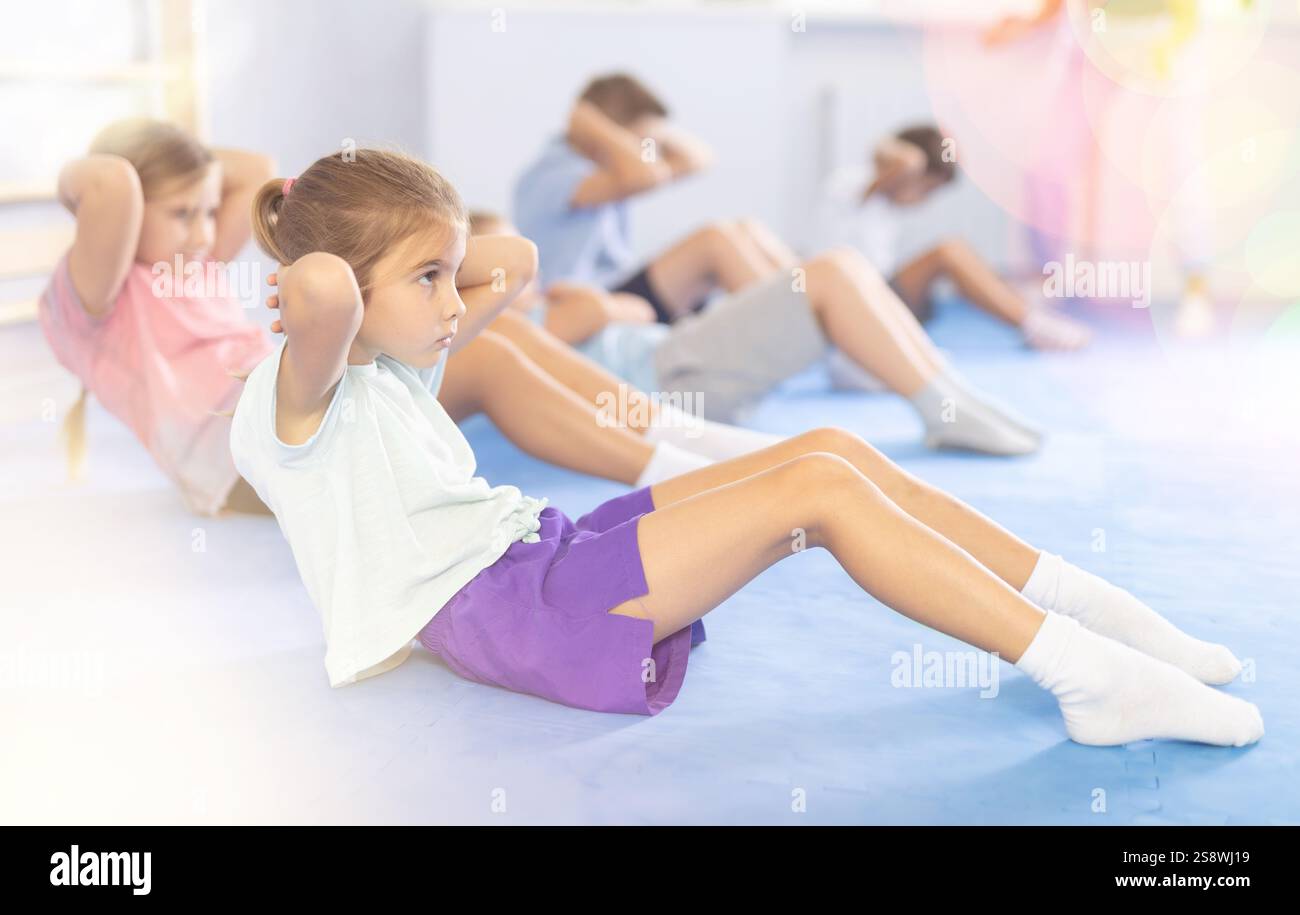 Child pupils performs exercises to strengthen press and do abdominal ...