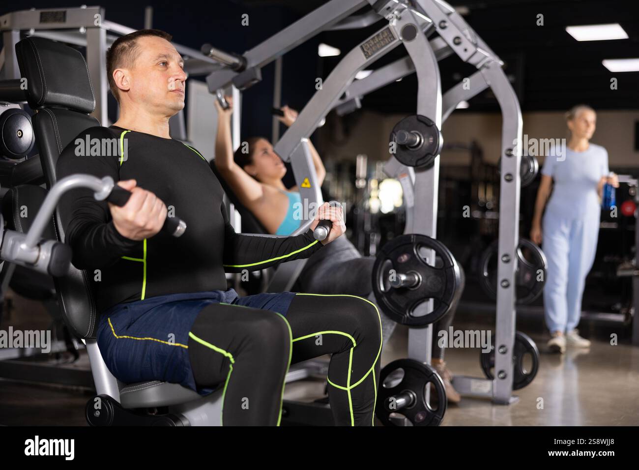 Focused sportsman working out arm muscles on the simulator in gym Stock ...