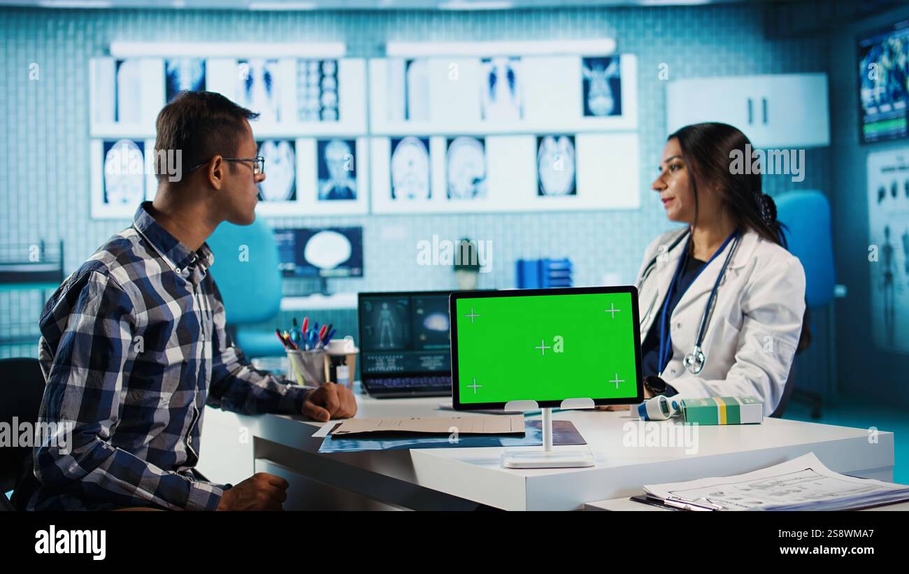 Indian physician consulting male patient in medical facility next to ...