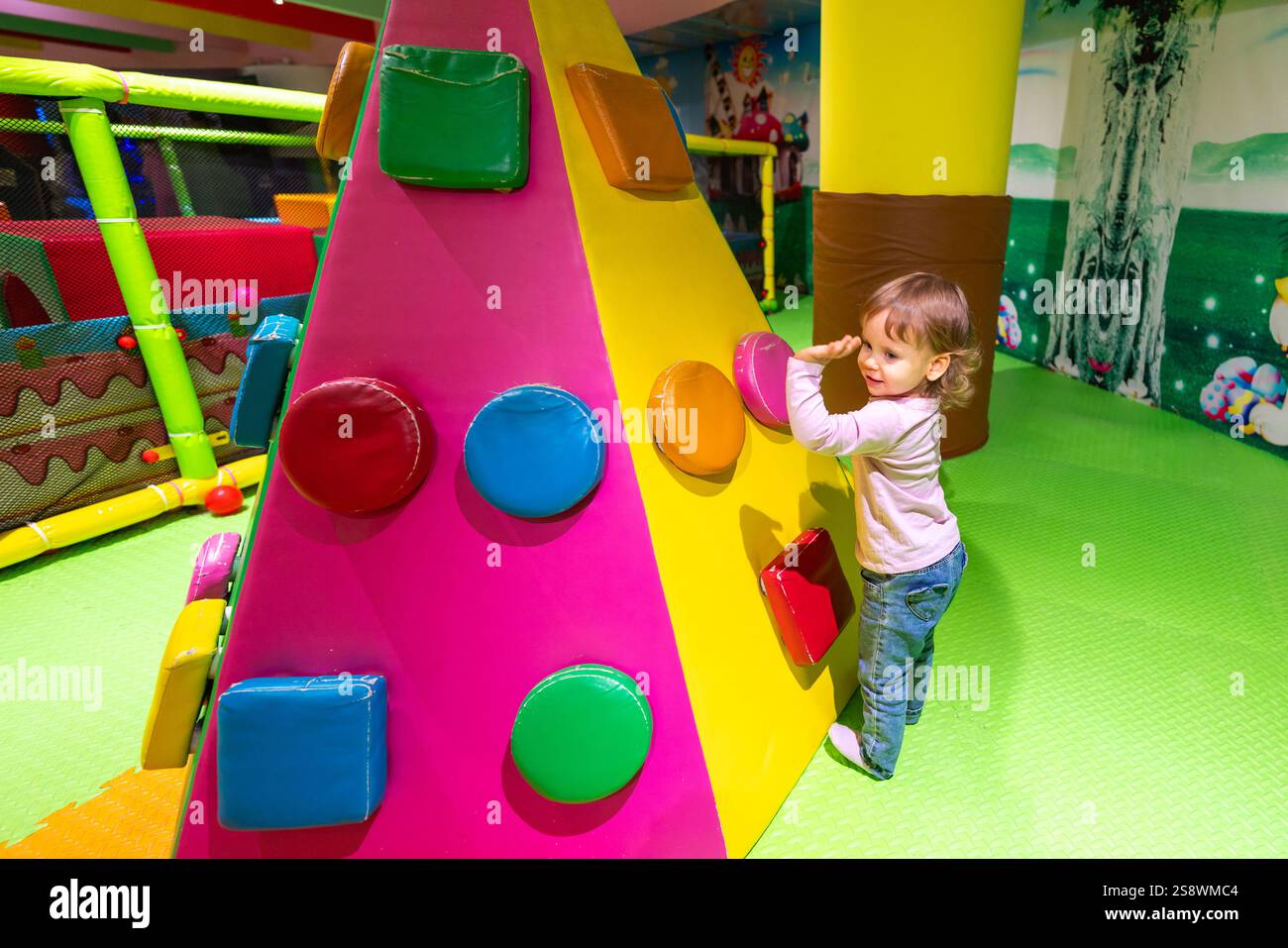 A child engaging with a colorful soft climbing pyramid in a cheerful ...