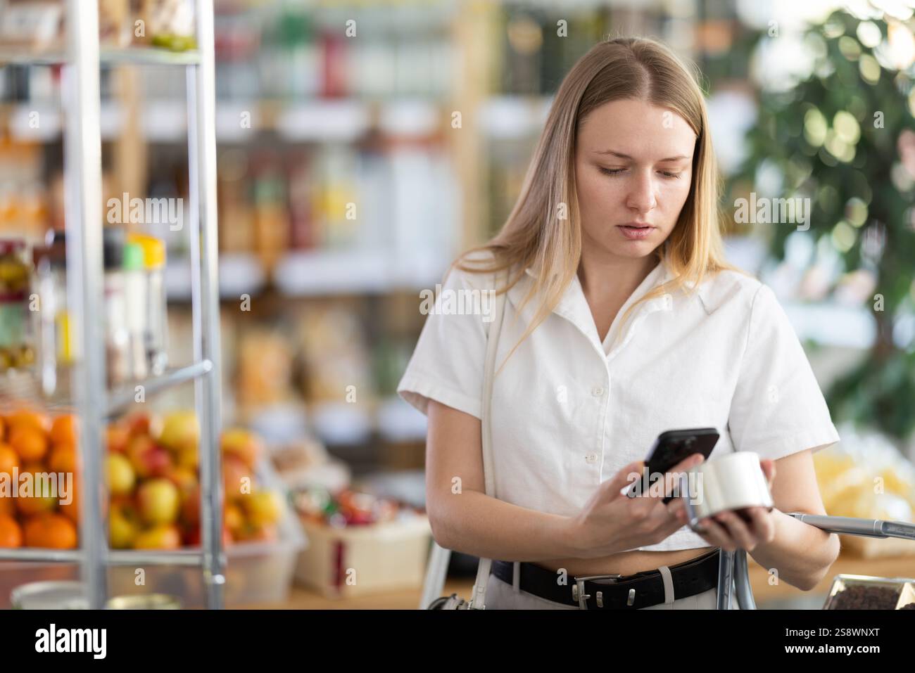 Female shopper scanning QR code or barcode on tin can label in grocery ...