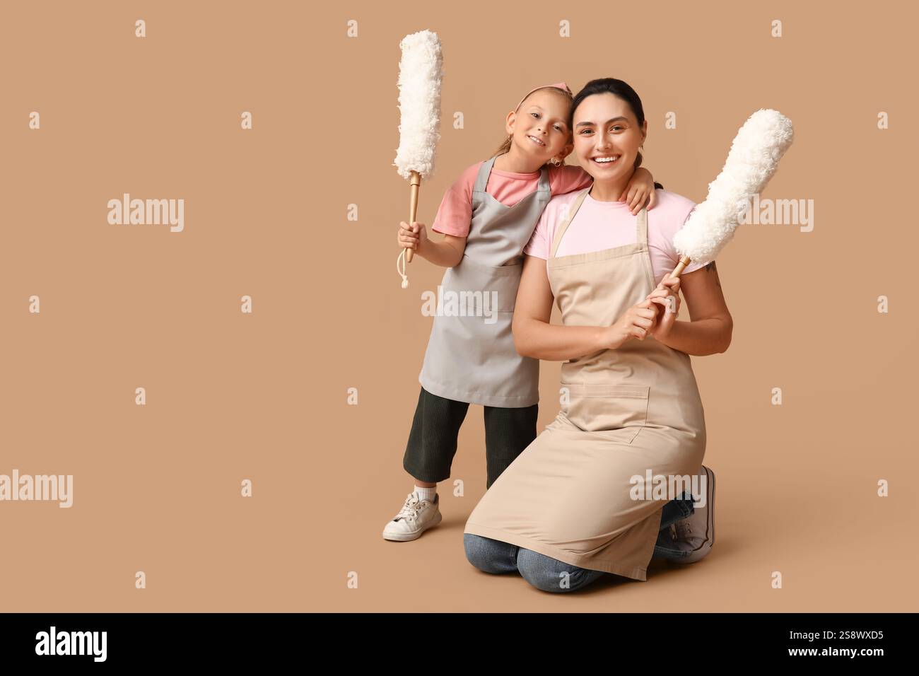 Happy mother and her daughter with pp-dusters sitting on beige ...