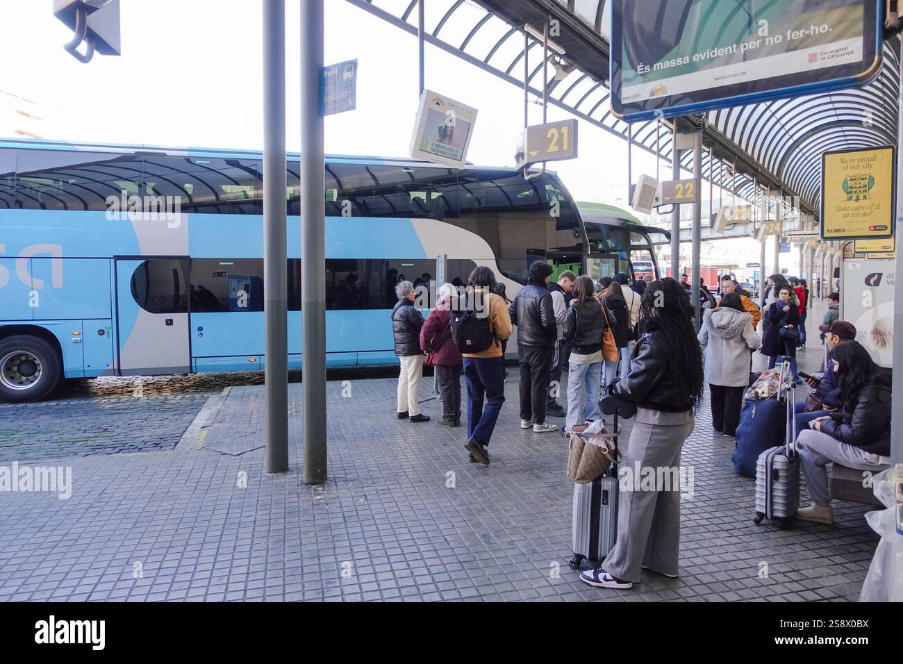 People standing and seated on benches at the platform at Barcelona Nord ...