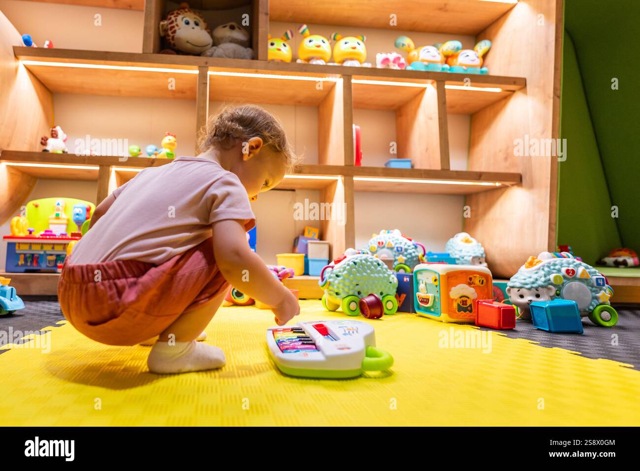 Toddler engaging with a colorful musical toy piano to boost creativity ...