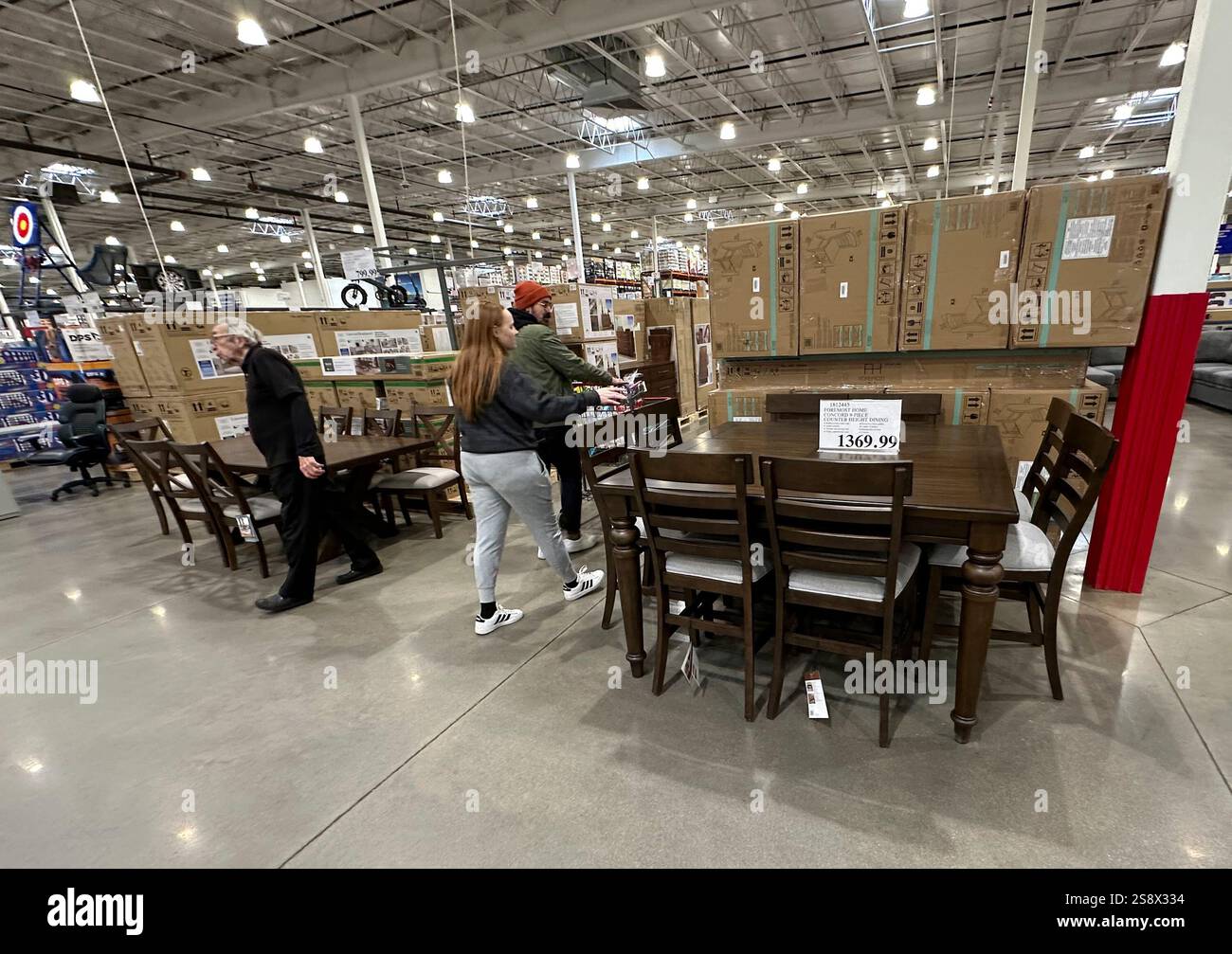 Shoppers pass by a dining room set on display in a Costco warehouse ...