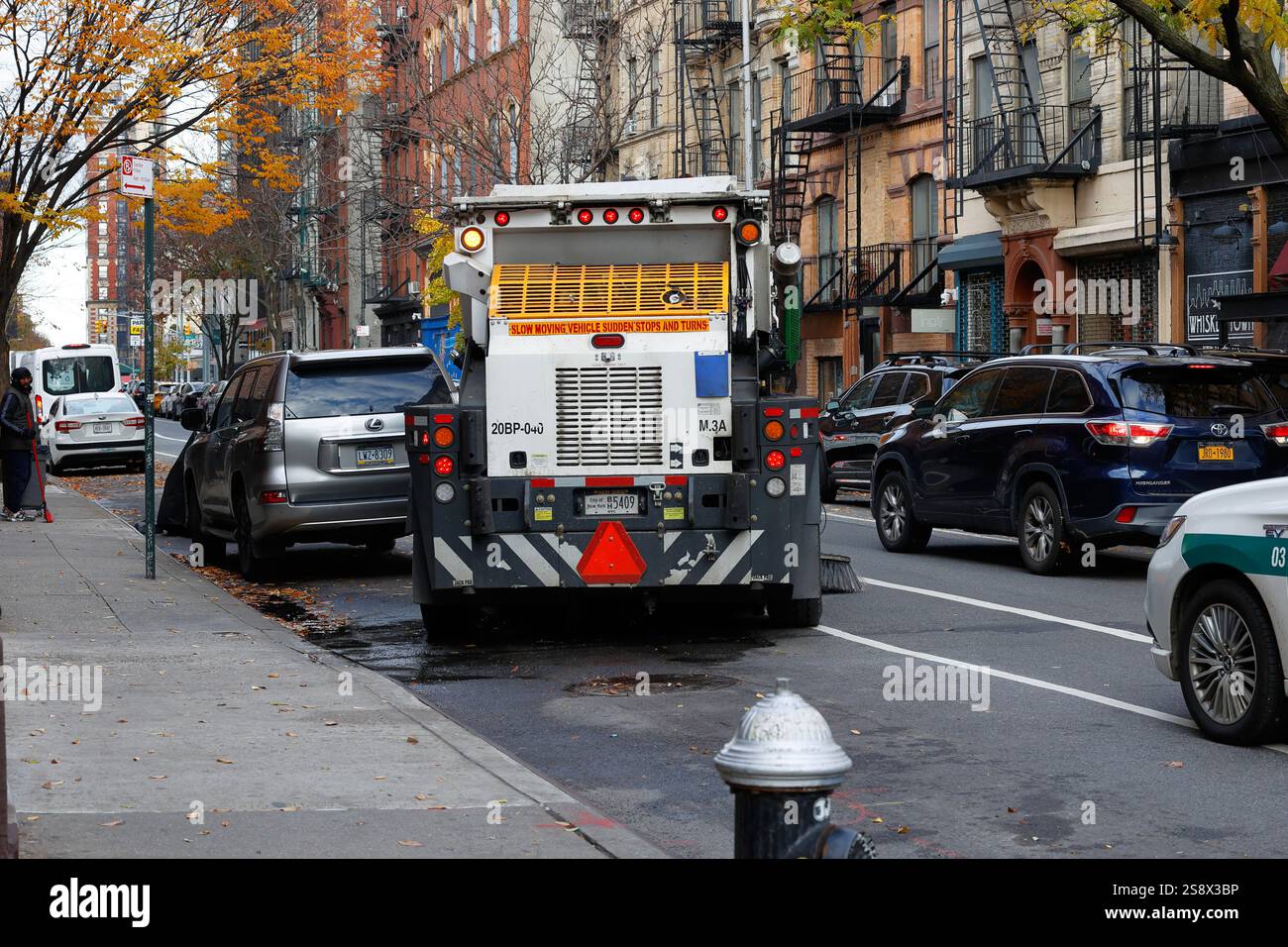 A NYC Sanitation department street sweeper maneuvering around parked ...