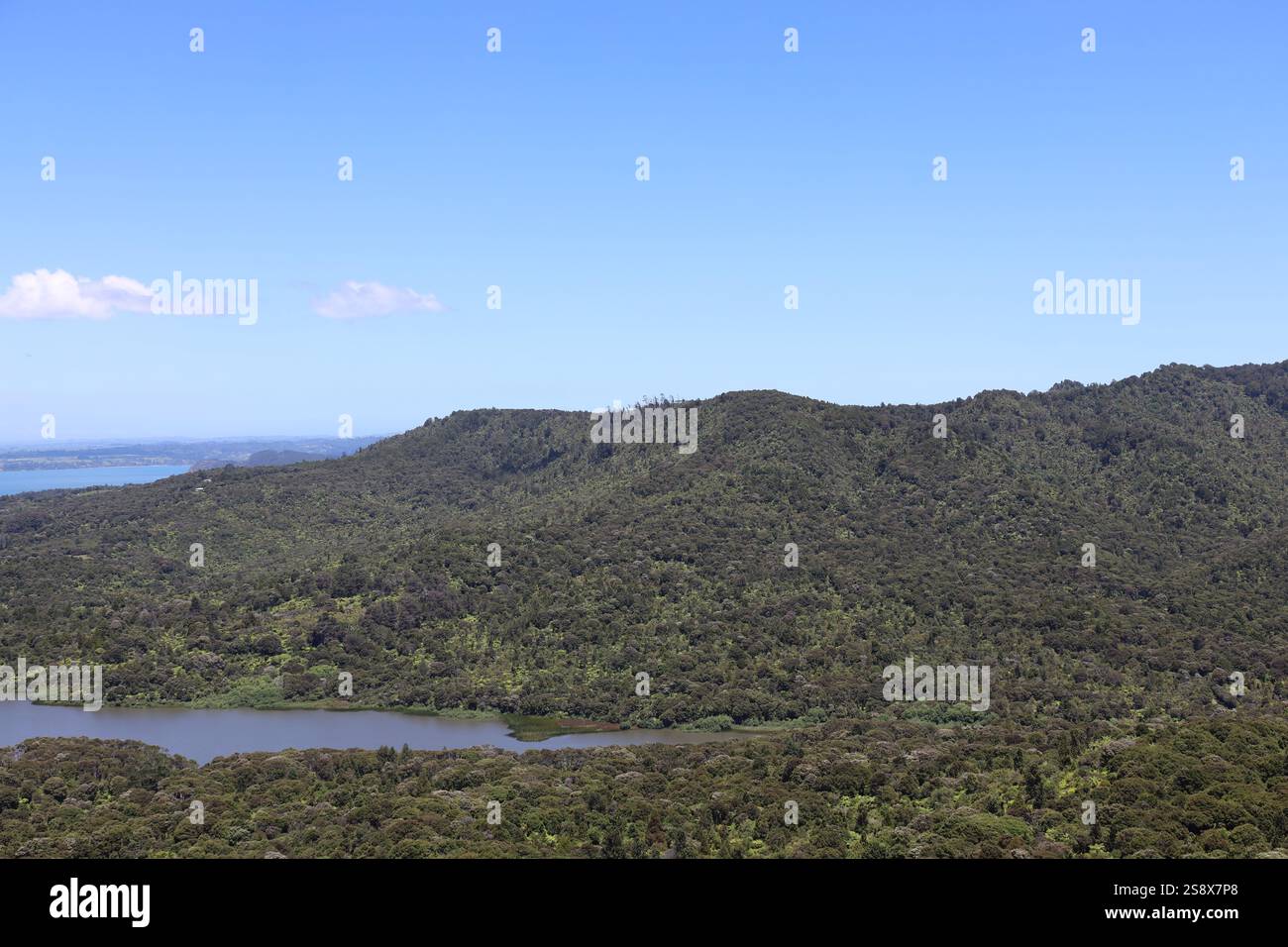 river tucked between forested rolling hills under cloudless deep blue ...