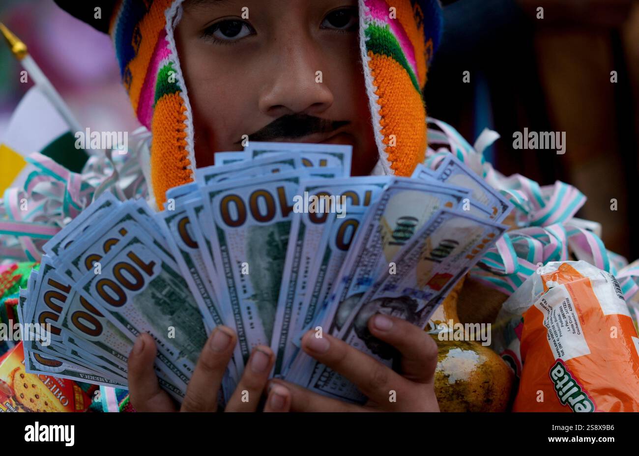 A child dressed as an Ekeko, revered as the god of prosperity, holds up ...