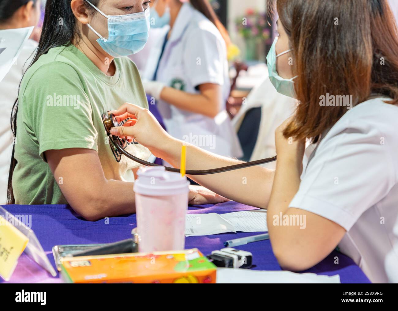 A doctor uses a stethoscope to check the heartbeat of her patient Stock ...
