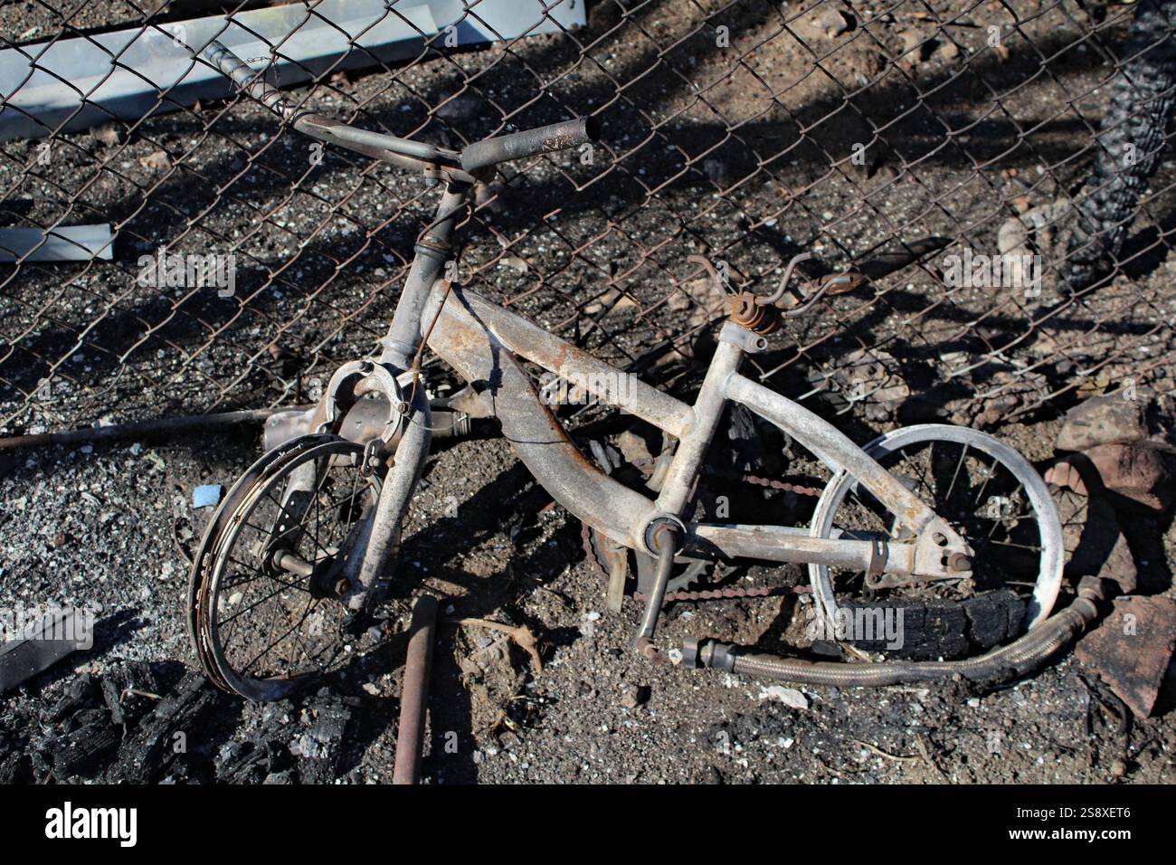 A burned bicycle sits near the debris of a damaged home in Altadena ...