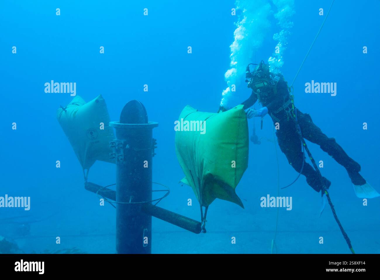 A commercial hard hat diver (MR) underwater, adjusts lift bags on a ...