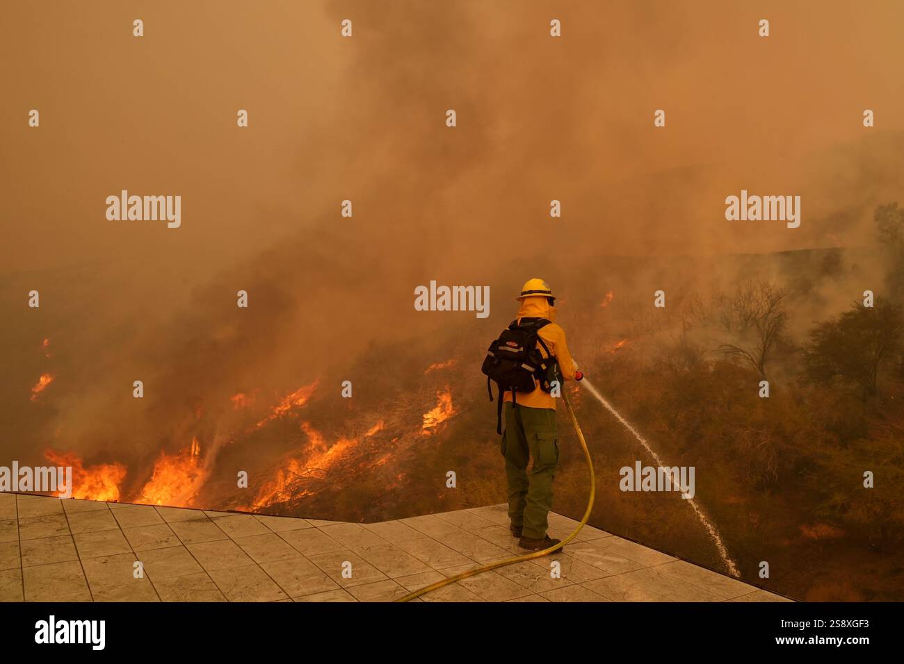 FILE - A firefighter hoses down flames as the Palisades Fire approaches ...