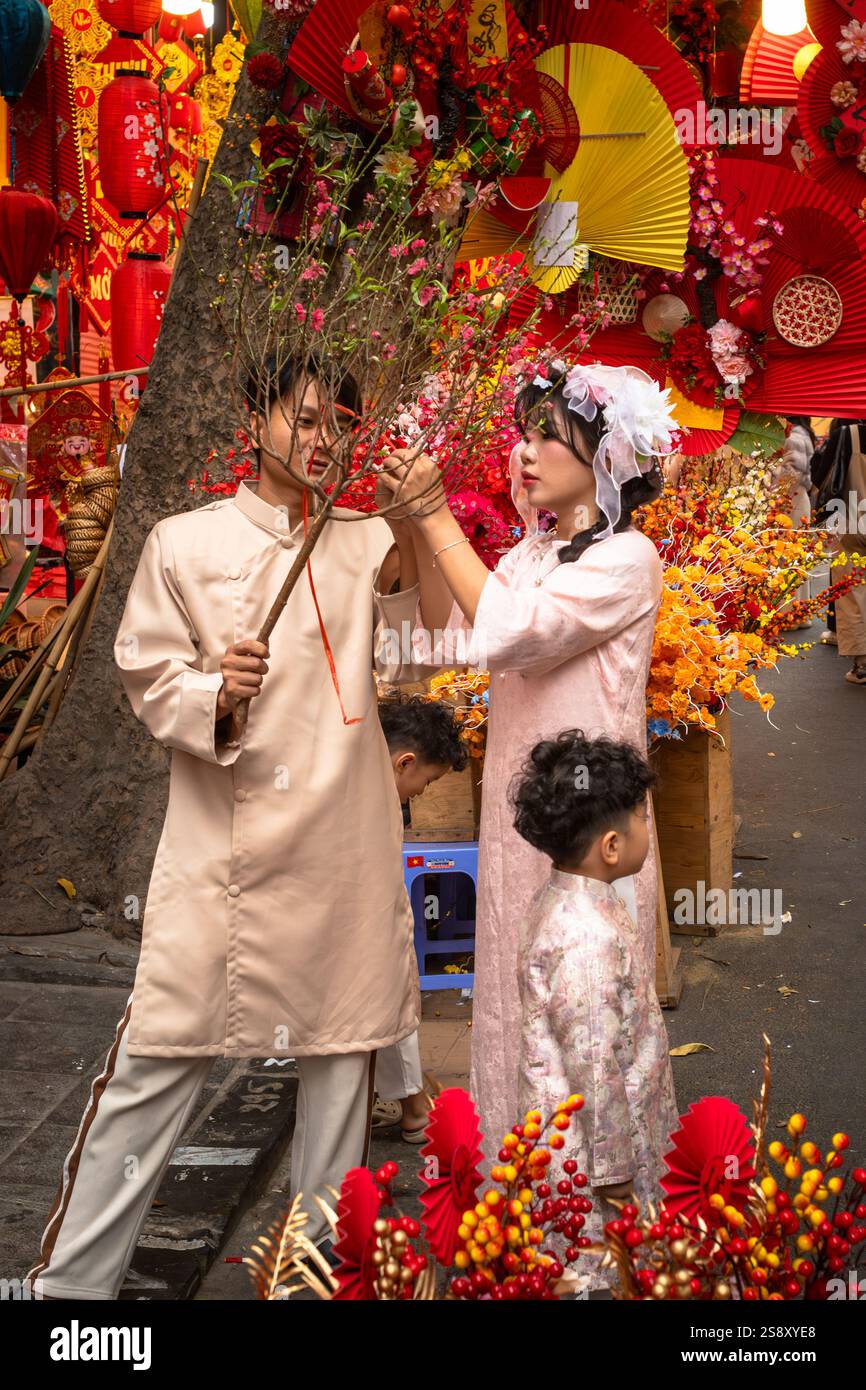 A young family dressed in traditional ao dai costumes and with a hoa ...