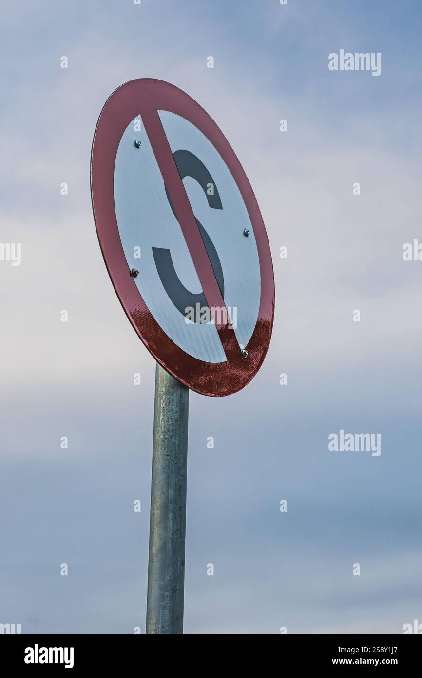 A close-up of a red and white circular traffic sign with a black "S ...