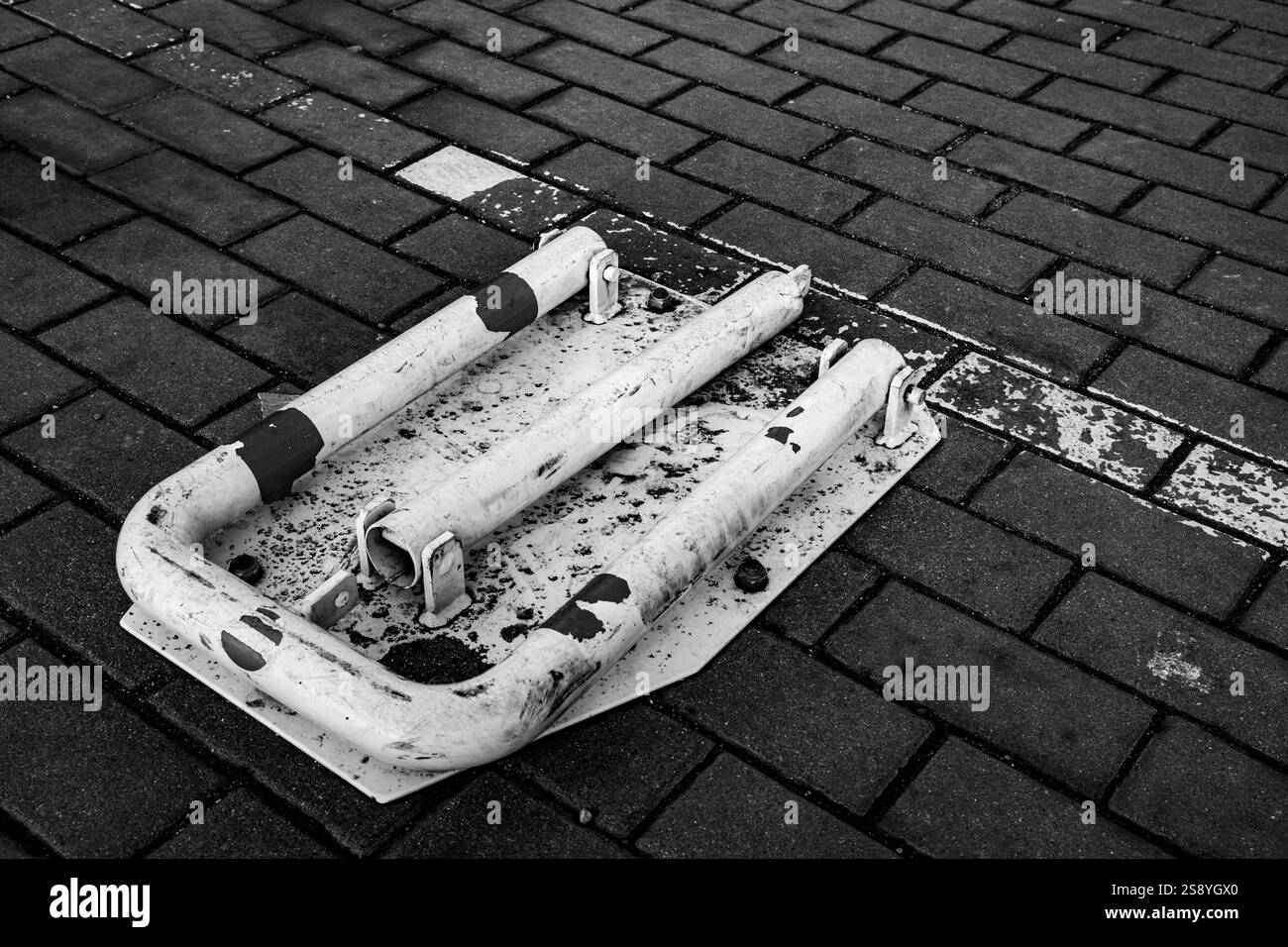 A metal obstacle lies on a paved walkway in a quiet urban setting ...