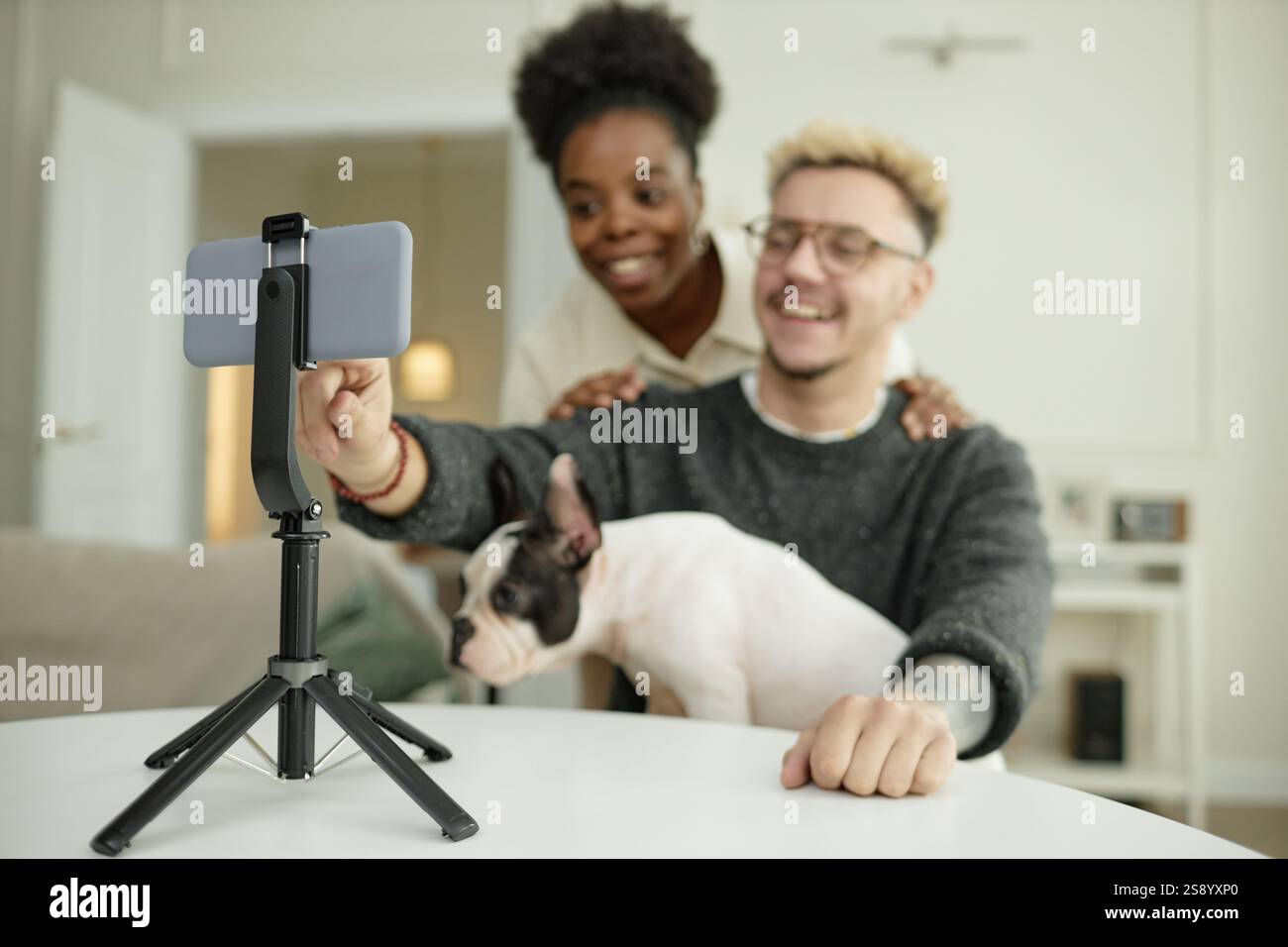 Shot of happy multiethnic couple with dog recording video on smartphone ...