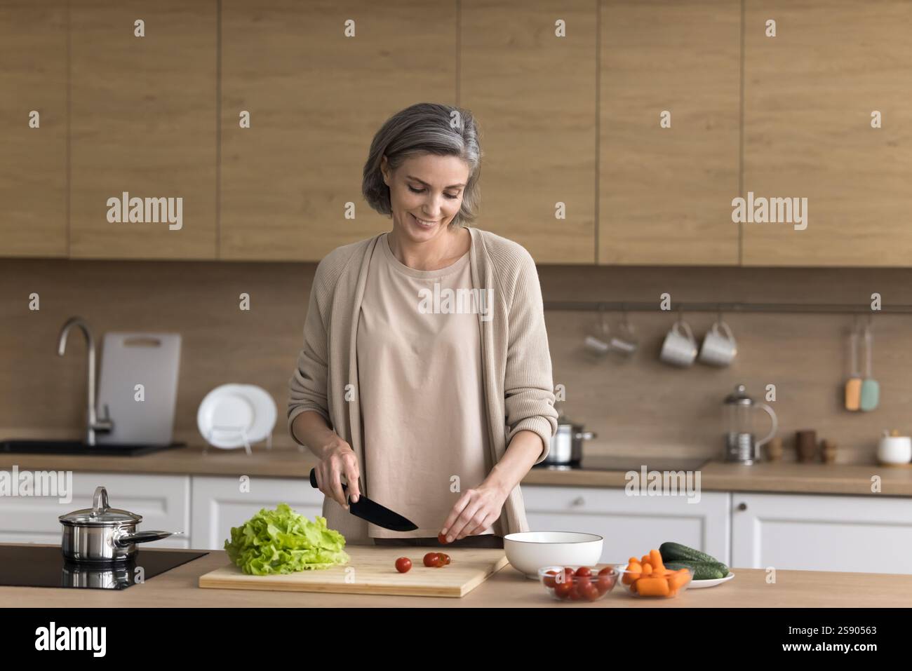 Smiling aged housewife cook food at domestic kitchen with love Stock ...